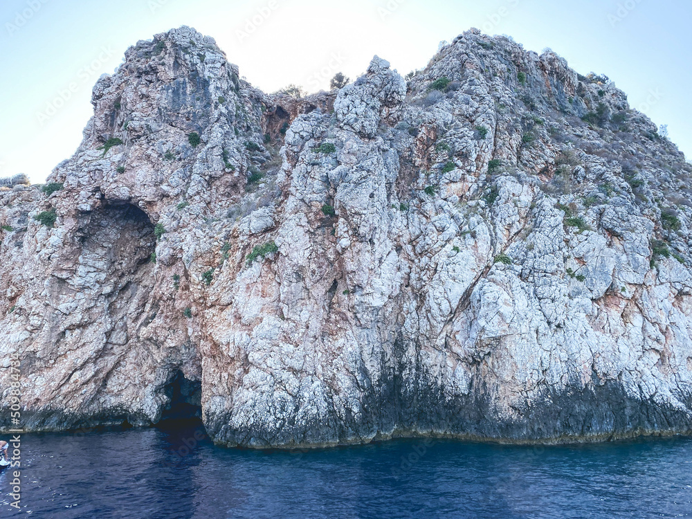 blue sea with white foam. near the water is a rock of white stone. a ...