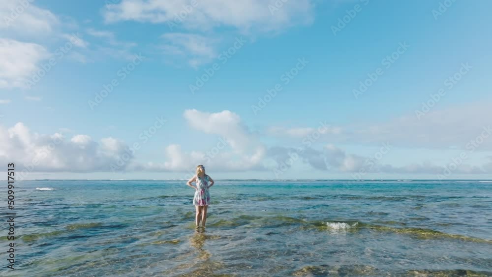 Cinematic aerial shot around young woman in beach dress staying in ...