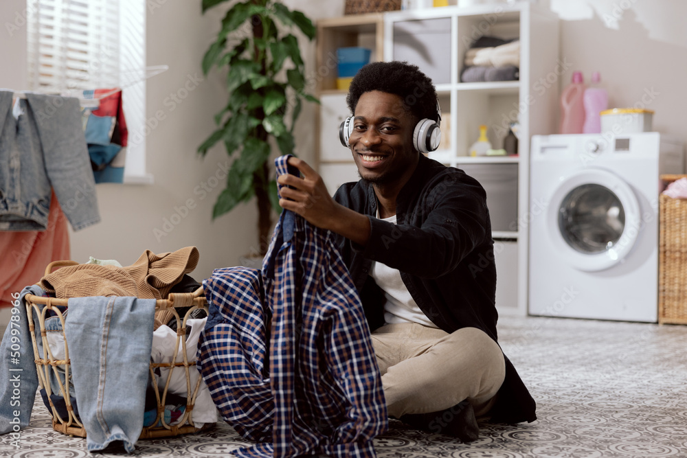 Portrait of asmiling young men folding clean clothes, sorting laundry ...