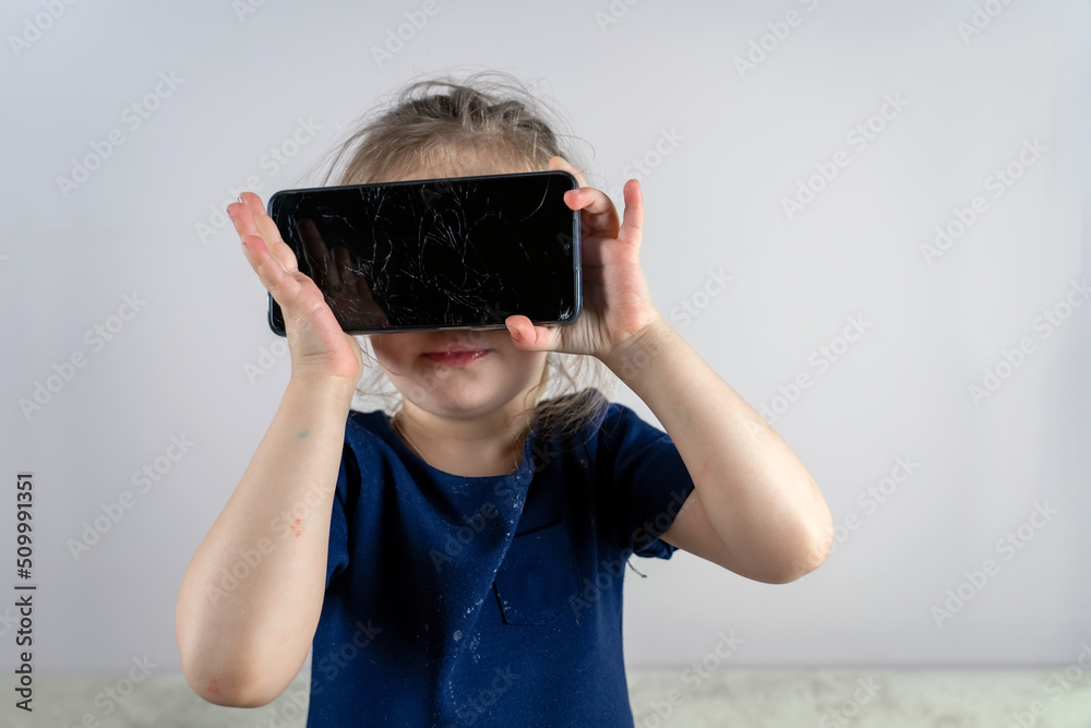 Portrait of terrified child with damaged phone. Upset little girl ...