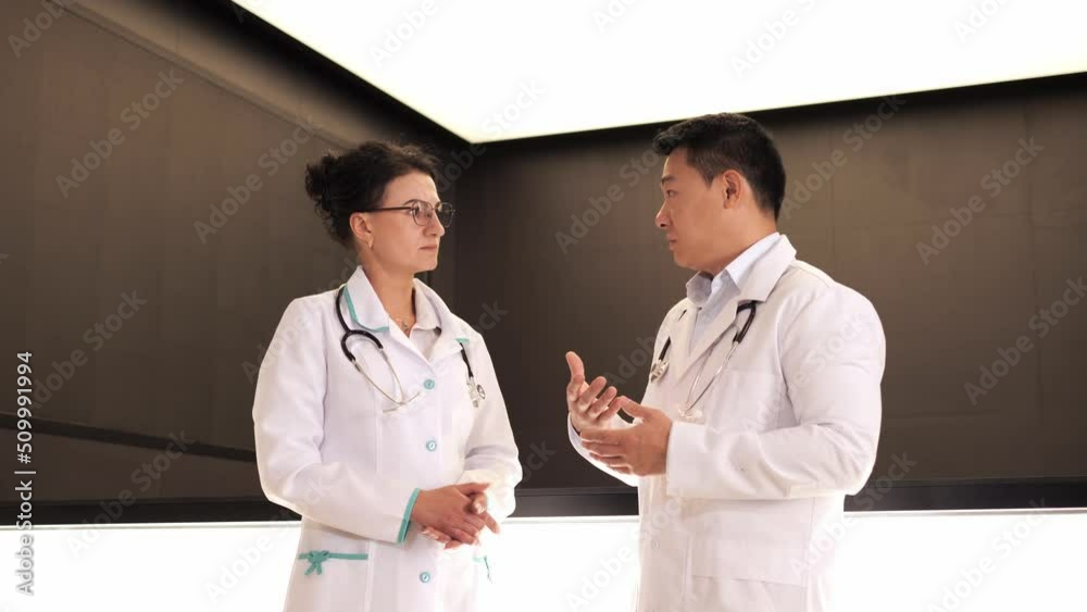 Vidéo Stock Modern white hospital, two multinational doctors standing ...
