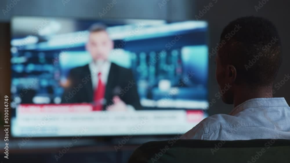Man Watches Late Night News Show on TV while Sitting on a Couch at Home ...