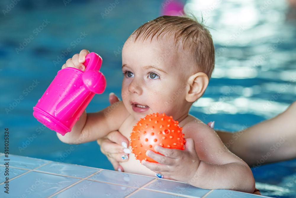 Little kid boy learns to swim and has fun in pool with mom support ...