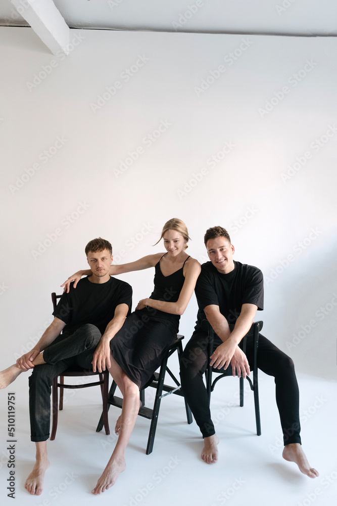 two brothers and sister in black clothes with bare feet in a light ...