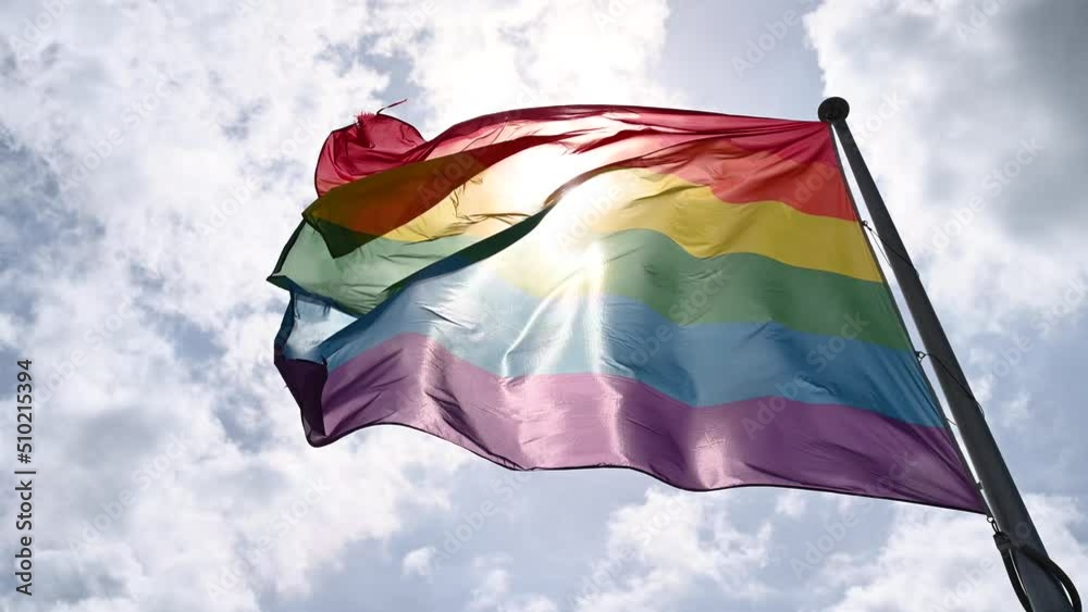 LGBTIQ flag waving on the wind on flagpole in town. A symbol of the ...