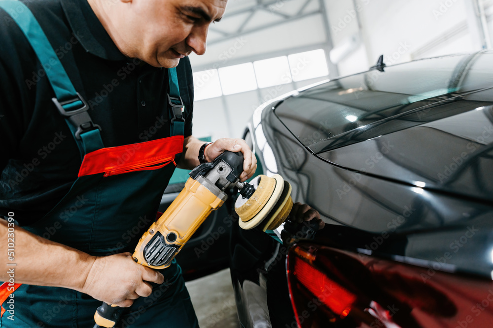 Professional car service worker polishing luxury car with orbital ...