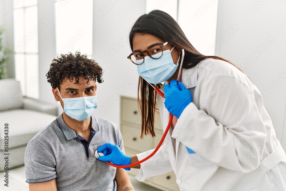 Young latin doctor woman auscultate heart man using stethoscope at ...