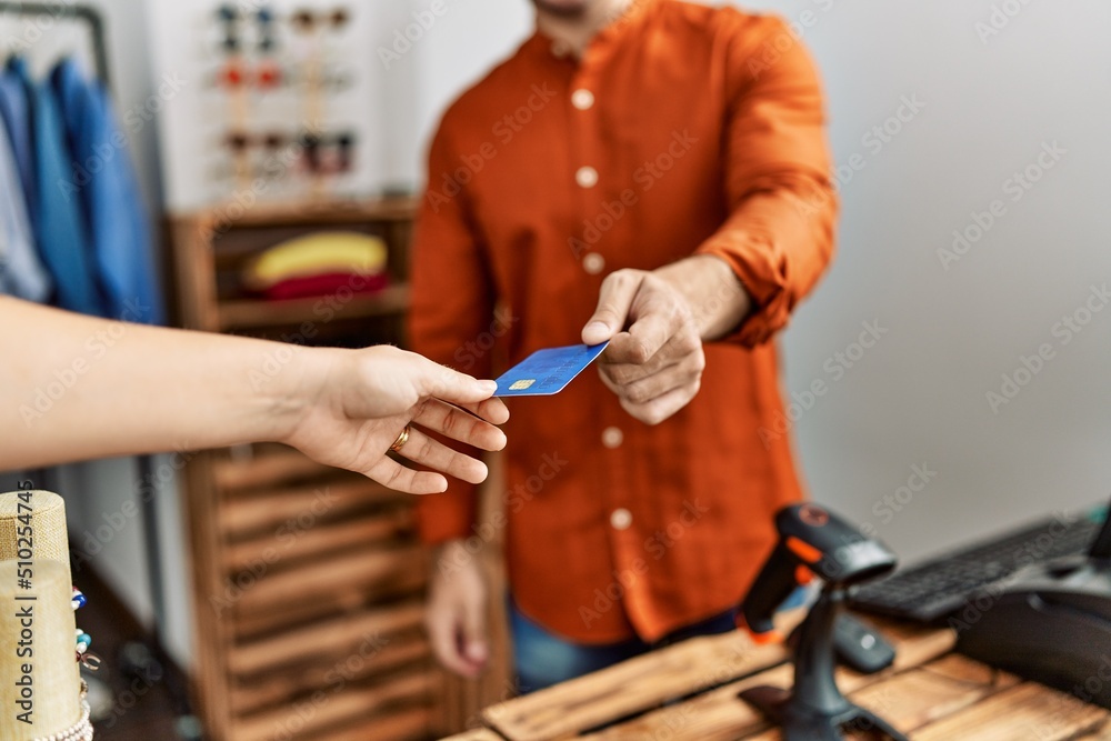 Hand of shopkeeper man giving credit card to customer at clothing store ...