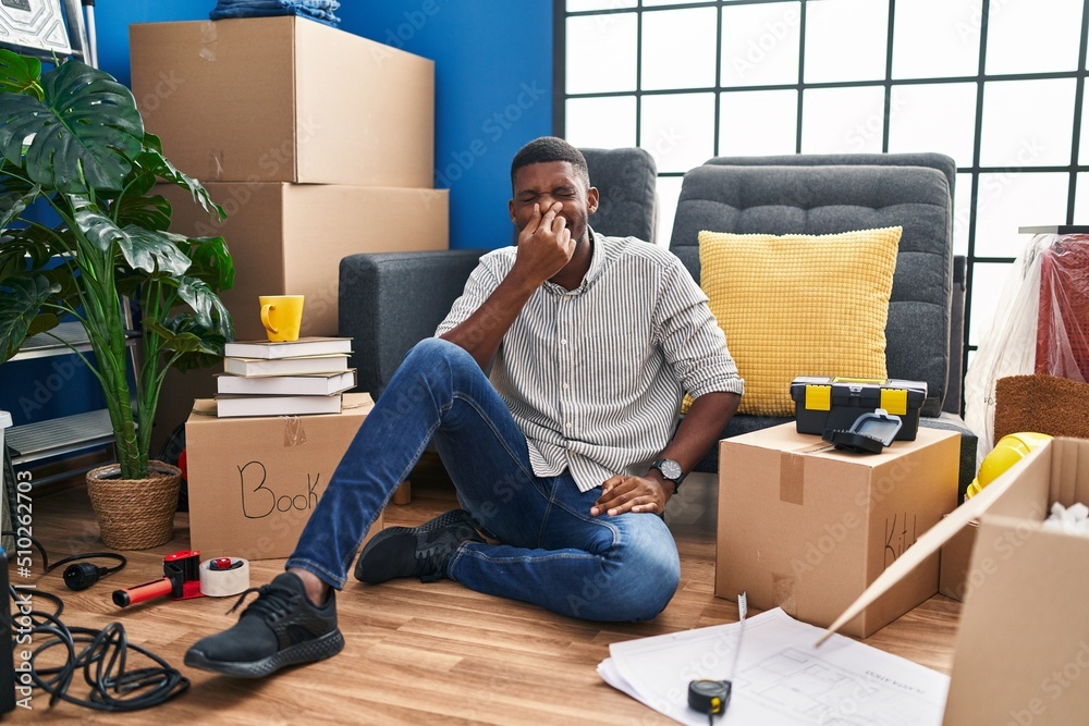 African american man sitting on the floor at new home smelling ...