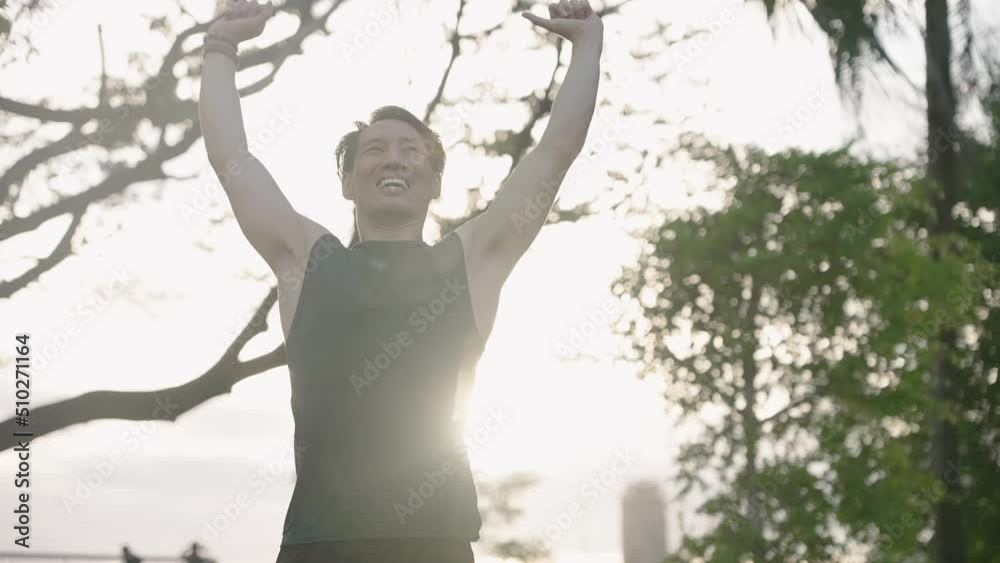 Fit Asian guy raising his arms feeling relief after finish with his ...