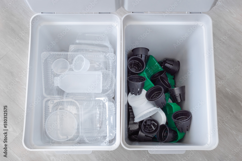 Sorting of plastic garbage in two grey recycling bins, filling garbage ...