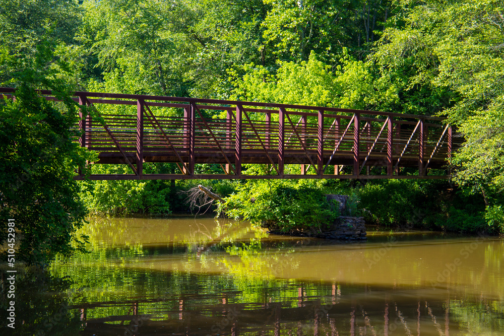 a long metal rust colored bridge over the silky brown waters of Little ...