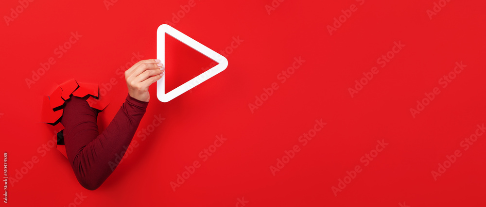 hand holding 3d media play button over red background, panoramic layout ...