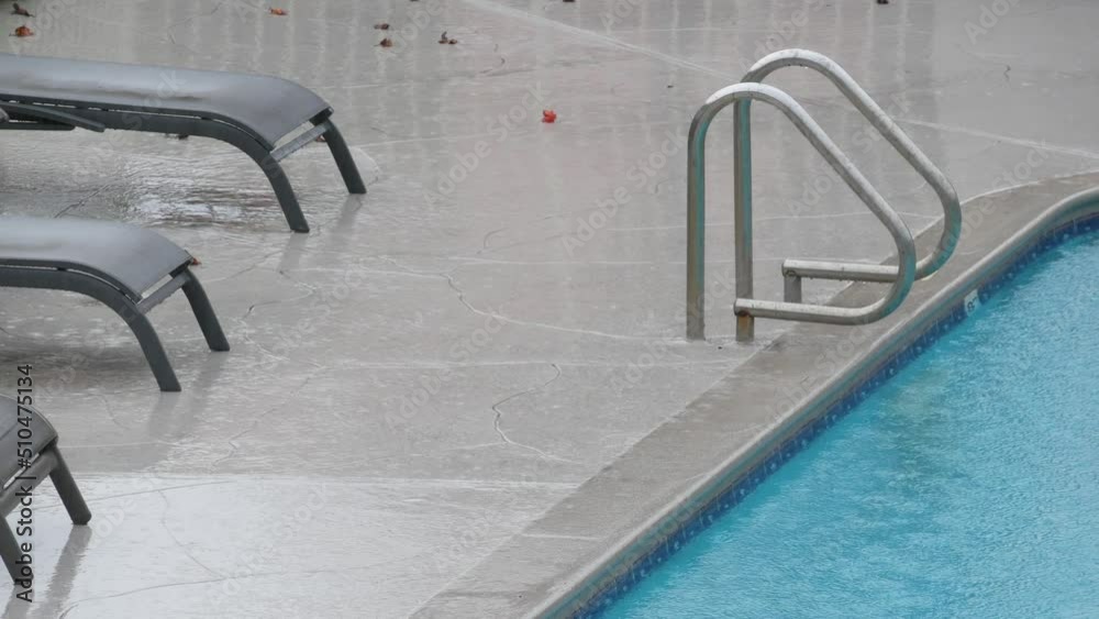 Rain drops falling on water surface of blue swimming pool, rainy day in ...