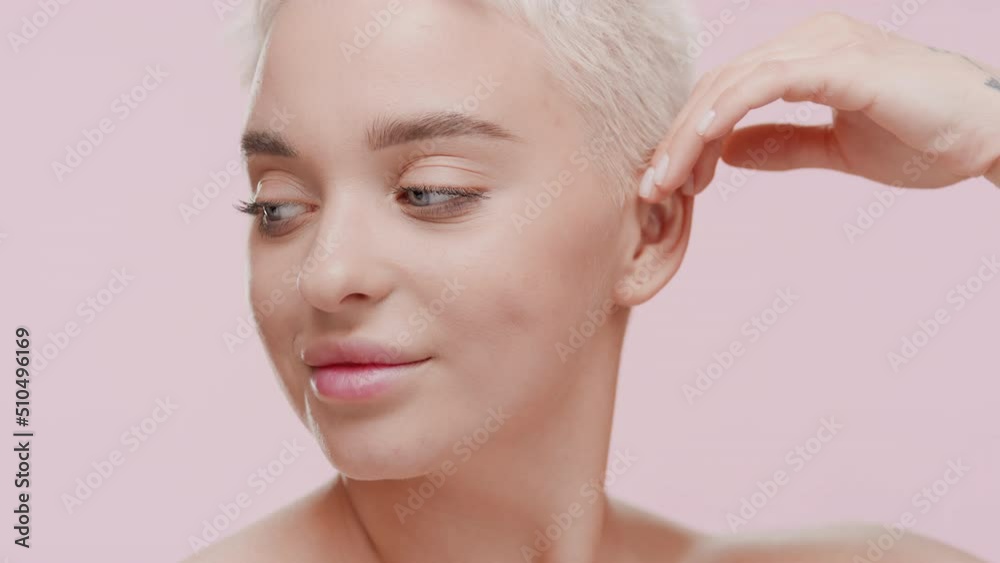 Beautiful young slim Caucasian woman with fair hair strokes her jawline ...