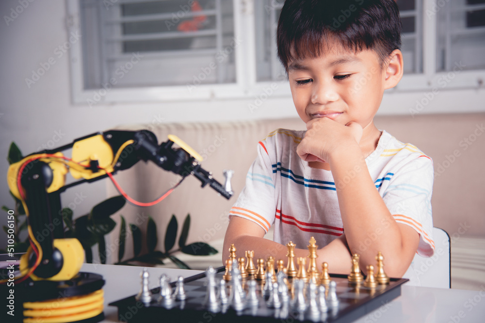 Asian little boy thinking and wait robot arm playing chess, STEM ...