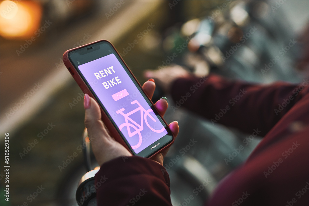 Woman Renting Bike Using Rental App On Mobile Phone Using Bike Sharing