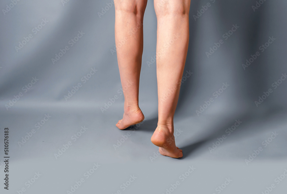 Slender female legs raised on toes on a light gray background Stock ...