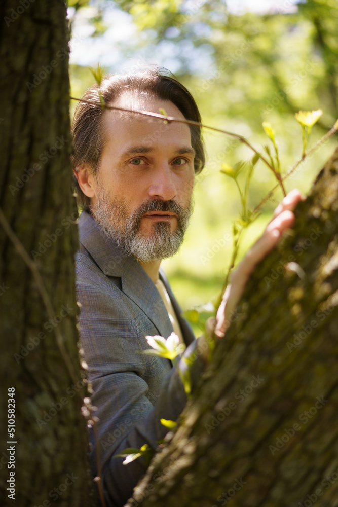 Mature grey beard businessman wearing casual grey jacket looking thru ...