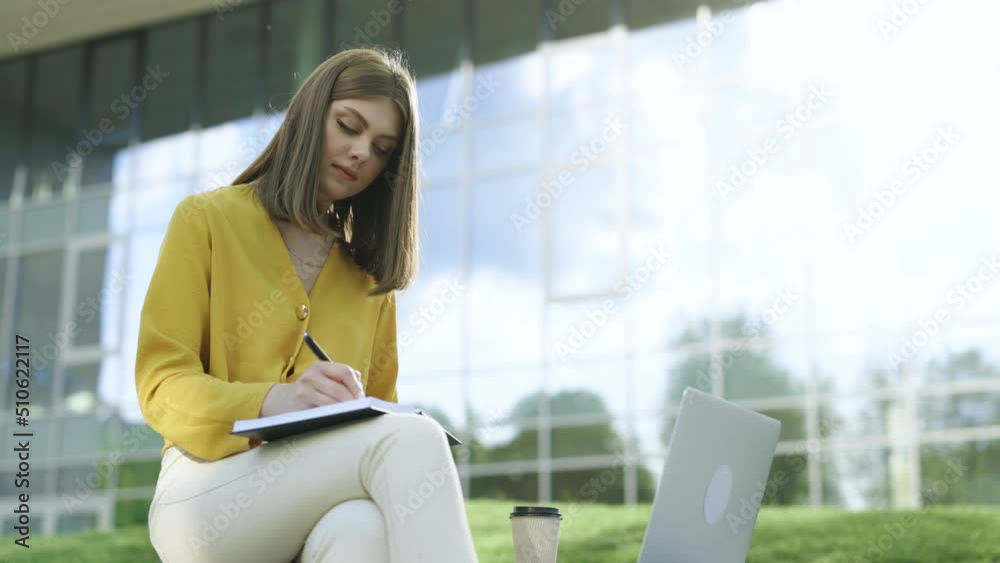 Portrait of focused student girl doing homework next to laptop computer ...