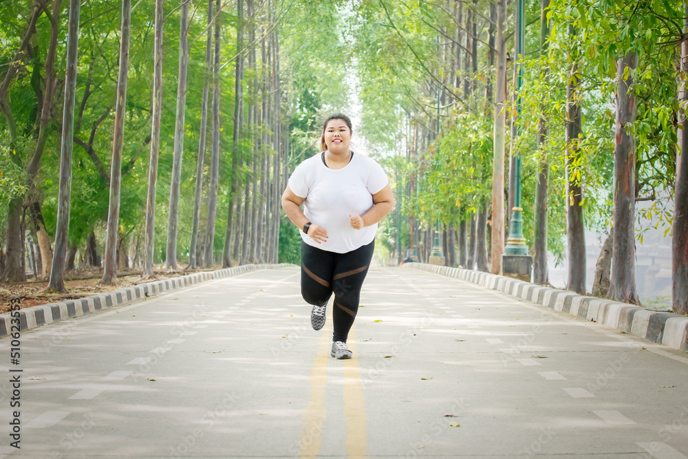 Overweight woman jogging at the park Stock Photo | Adobe Stock