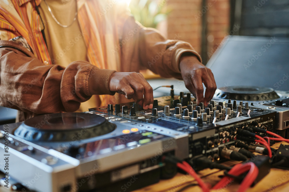 Hands of modern black man regulating sounds on dj set while standing by ...