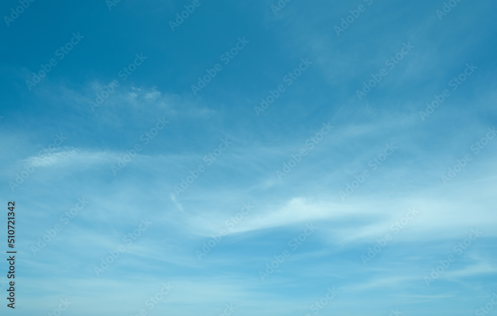 The wind blows the soft clouds against a clear blue sky background ...