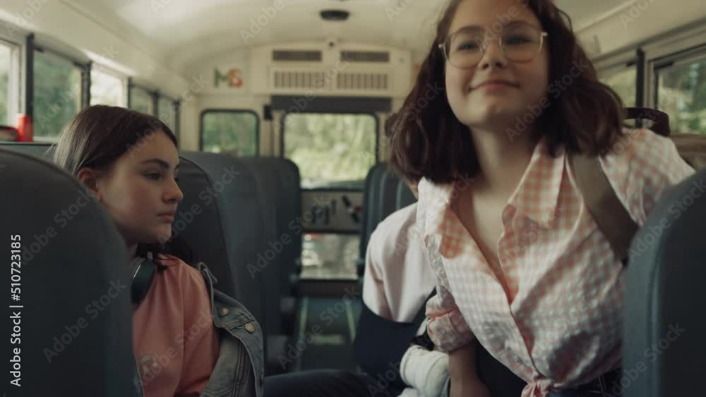 Three teenagers sitting school bus talking alone. Smiling girl taking ...