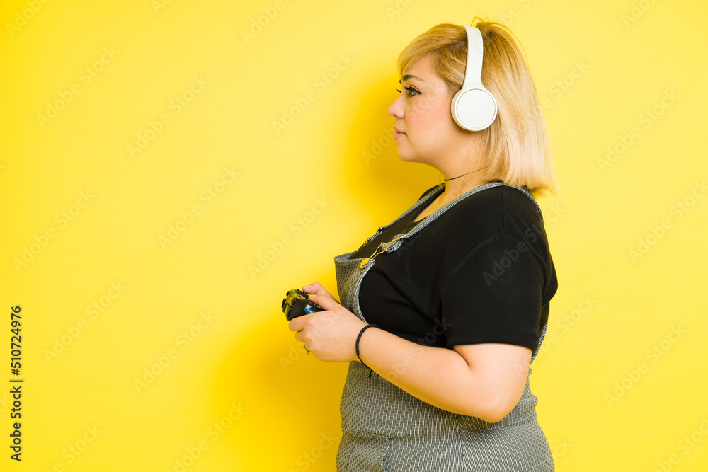 Fat gamer girl playing video games while wearing headphones in a studio ...