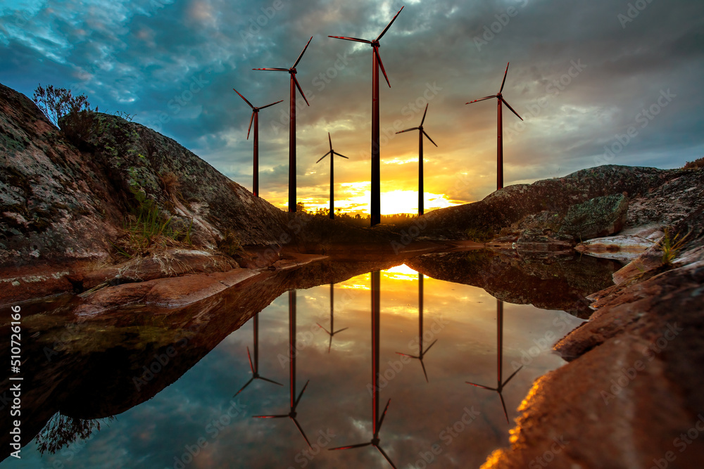 Wind generators are reflected in water. Windmills in rocky area ...