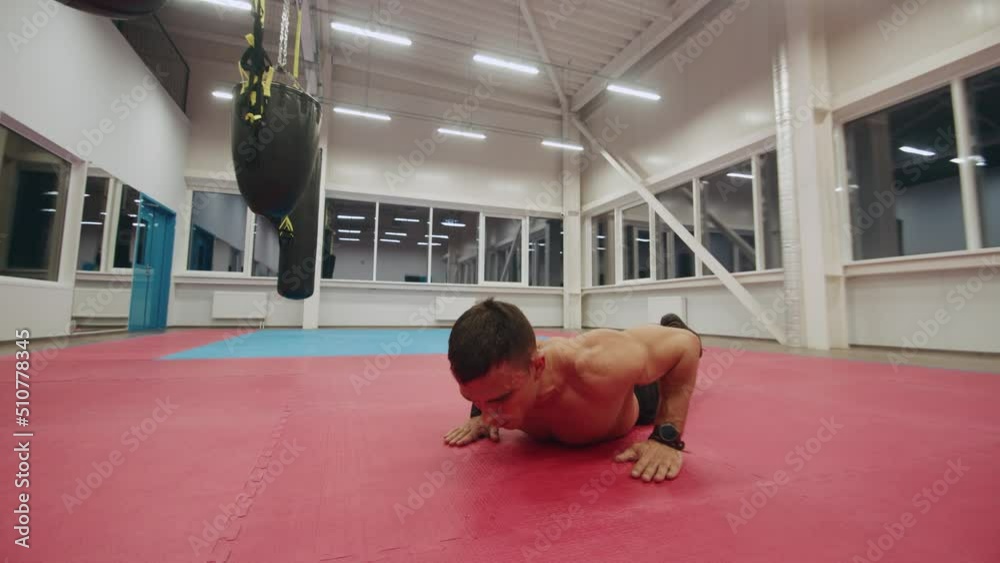 A bodybuilder performs swings with his arms and legs in the plank ...