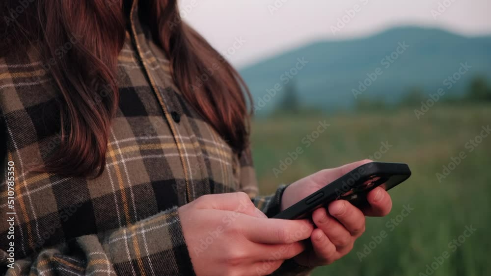 Close-up of female hands using smartphone standing of background summer ...