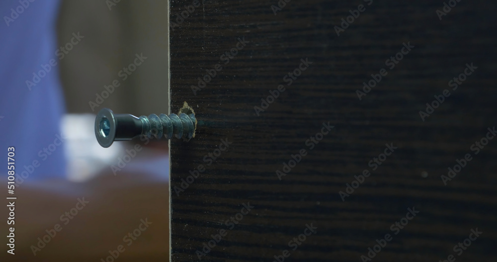 Man using an electric hand drill to drive a screw into a board. Dust ...