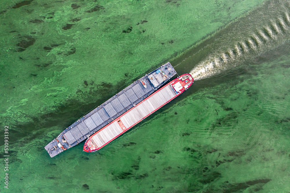 Two barges loaded with grain are sailing down the river to a commercial ...