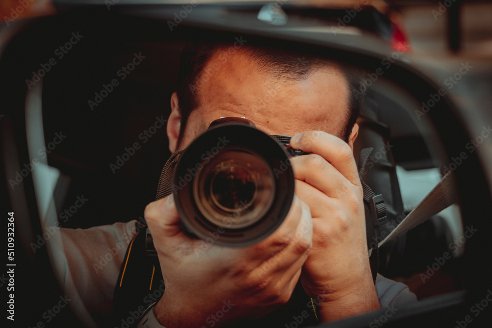 young man taking a photo with his camera looking at the viewfinder from ...