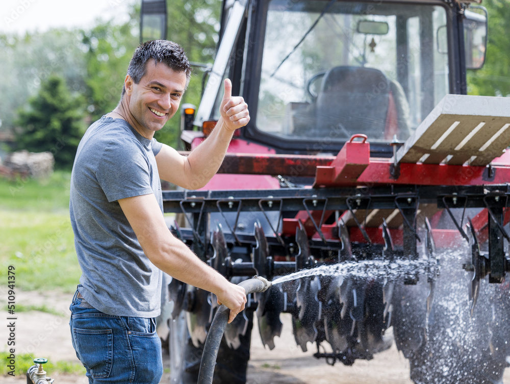 Farmer washing tractor with equipment on farm Stock Photo | Adobe Stock