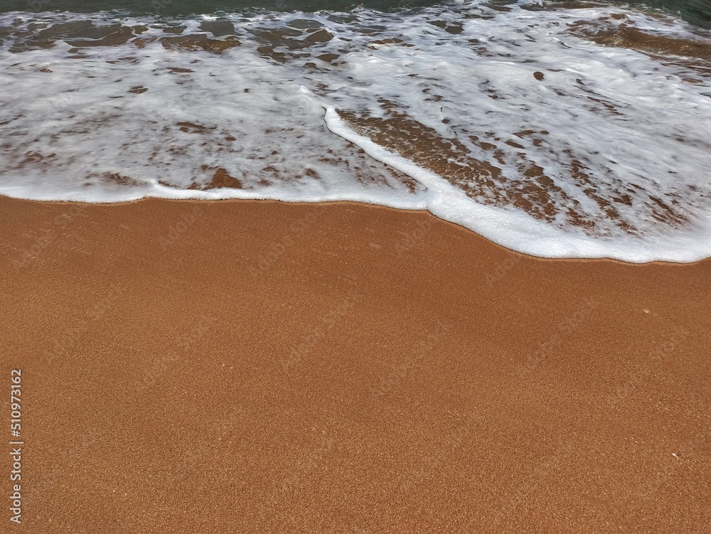 Sea foam on beach sand with clear water on a tropical butterfly beach ...