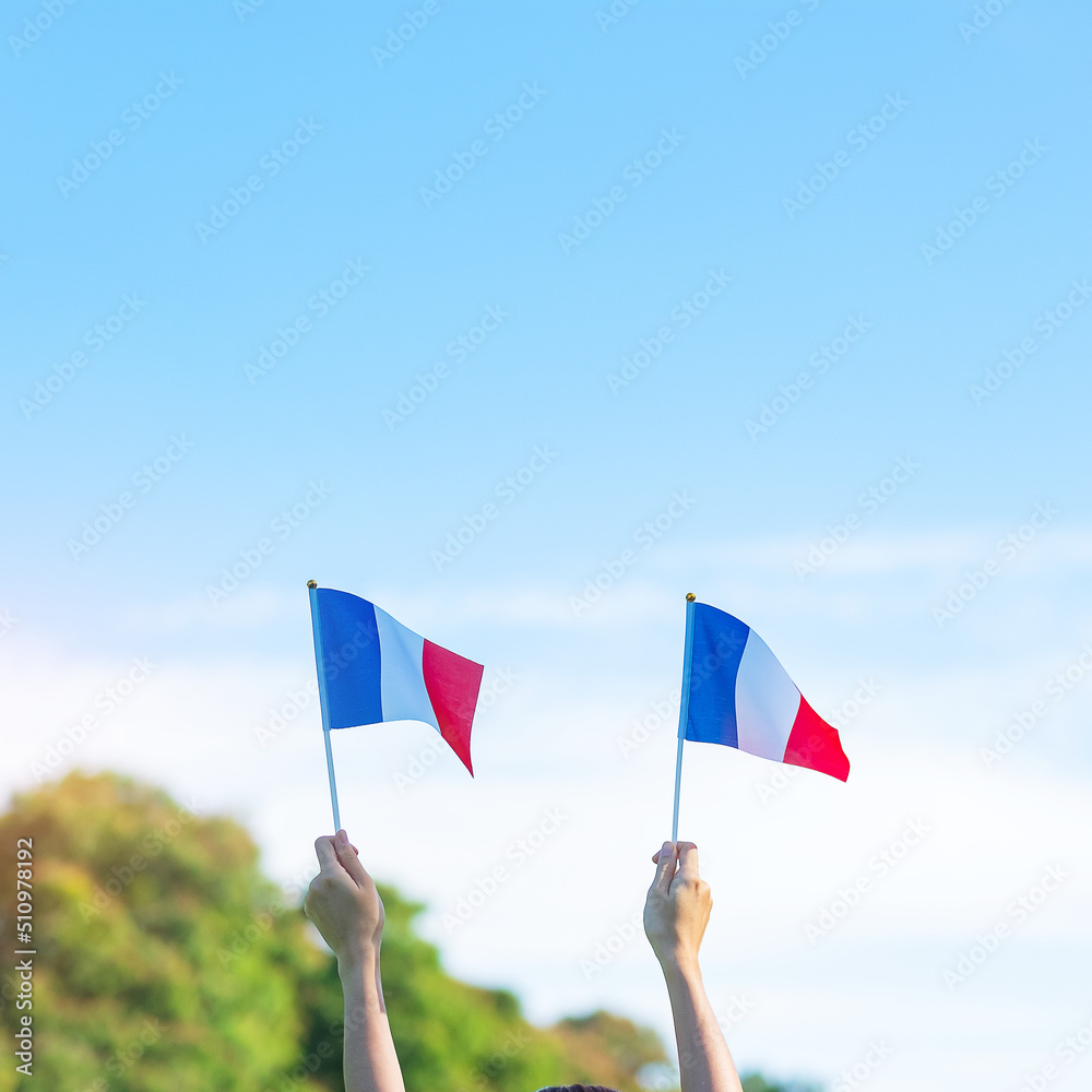 hand holding France flag on blue sky background. holiday of French ...