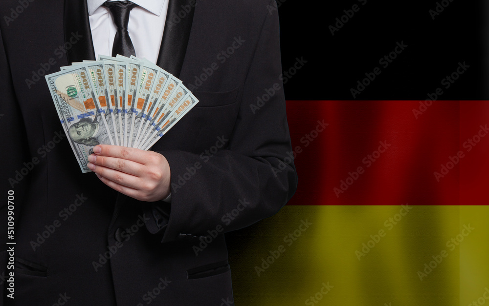 German business man hand holding US 100 dollar bills against flag of ...