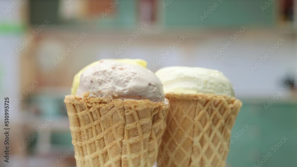Three color ice creams in waffle cups rotating in the kitchen in slow ...
