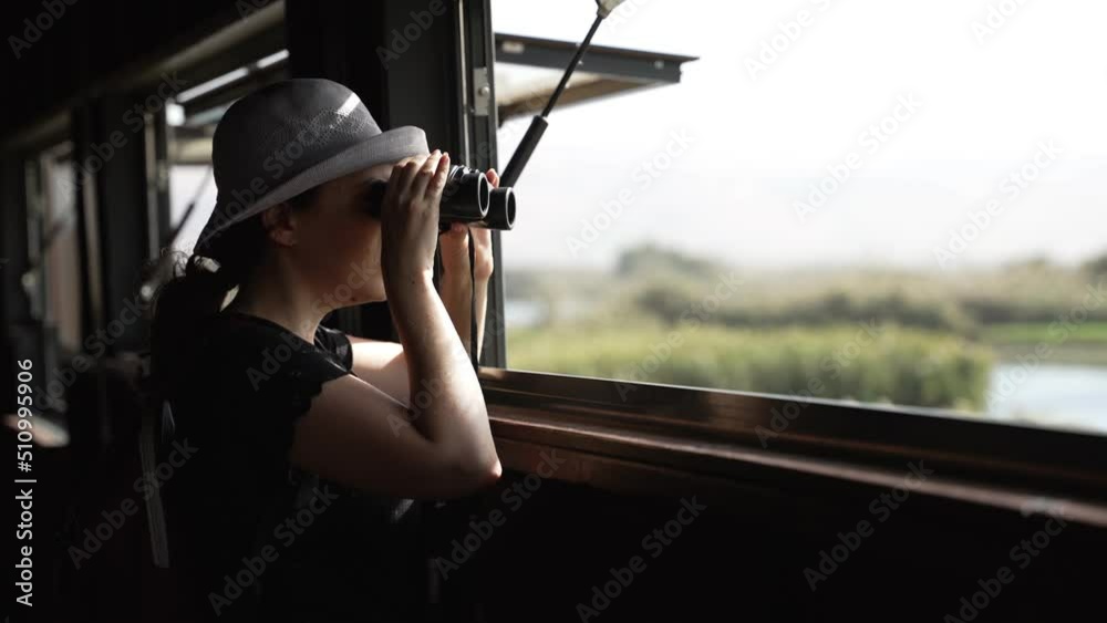 Woman birdwatcher standing at observatory looking for birds with ...