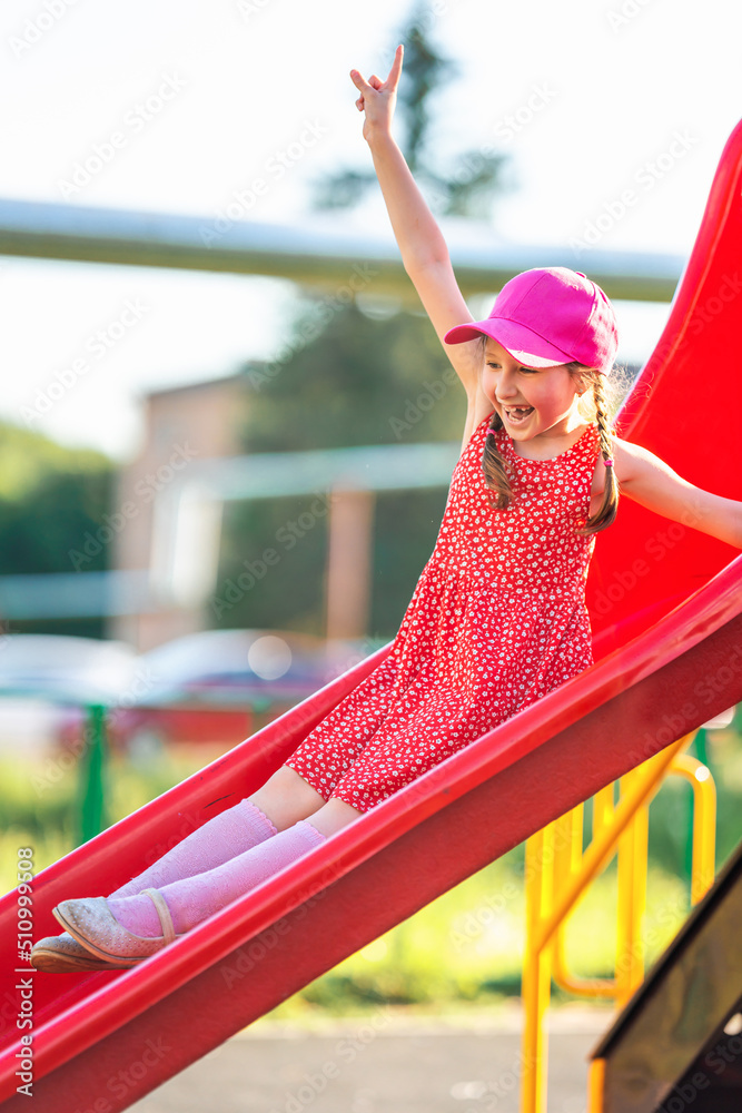 happy little Caucasian girl playing on a slide, A preschool child on ...