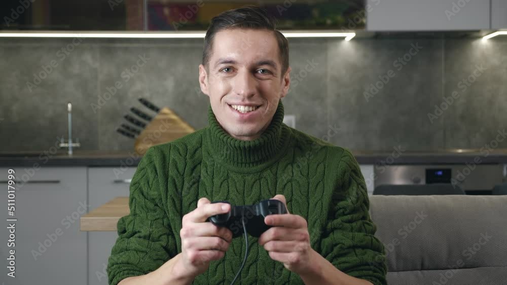 Happy man gamer holding controller playing video games while sitting on ...