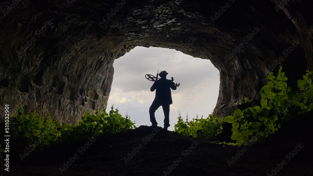 treasure hunter with metal detector searching inside the cave in the ...