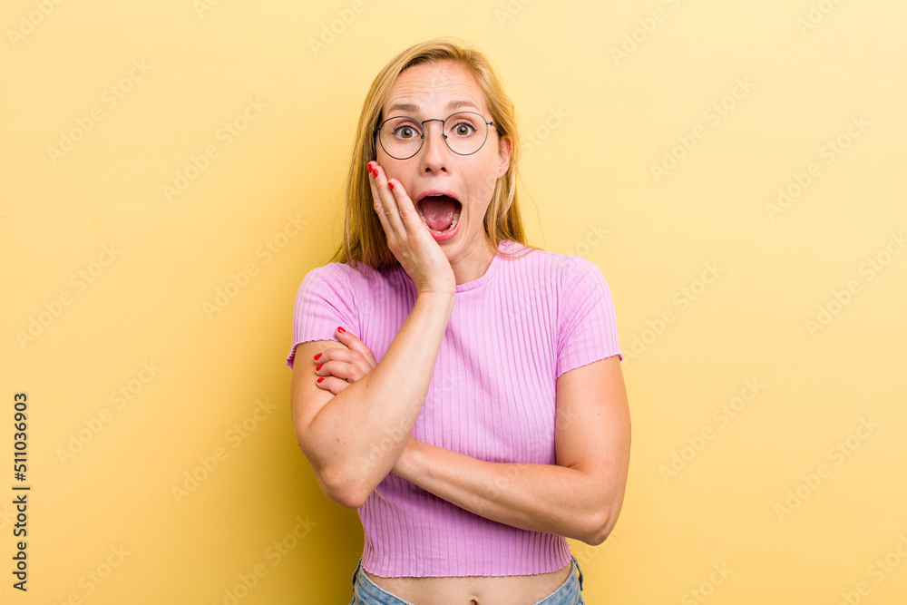 young adult blonde woman open-mouthed in shock and disbelief, with hand ...