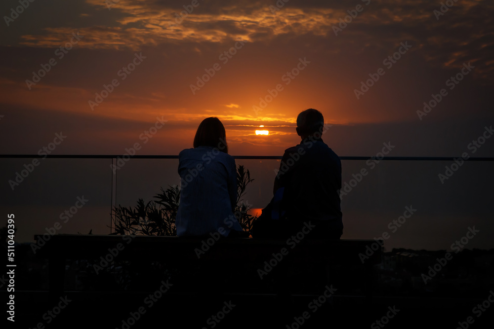 Two people, men and women, look at the sunset. Stock Photo | Adobe Stock