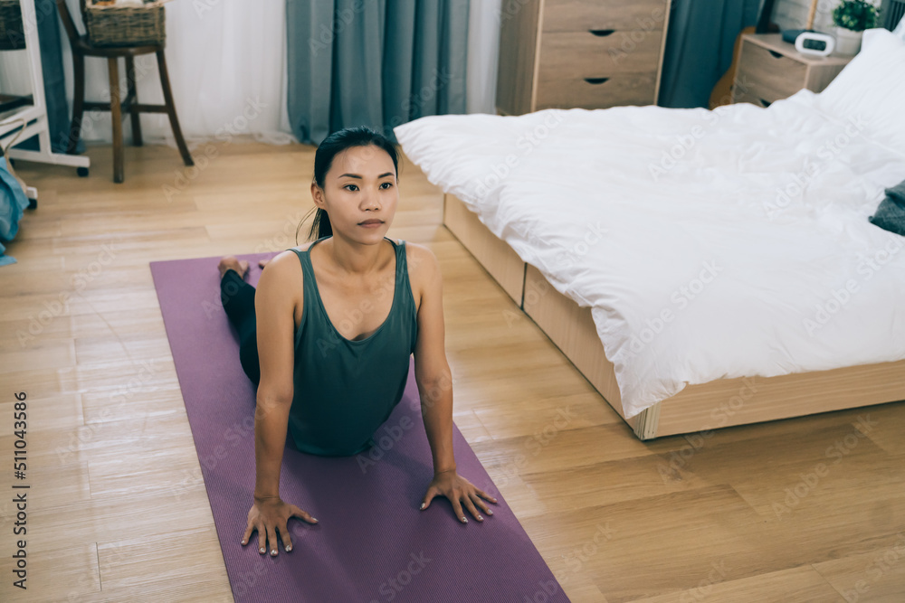 high angle view asian girl in workout apparel performing cobra pose in ...