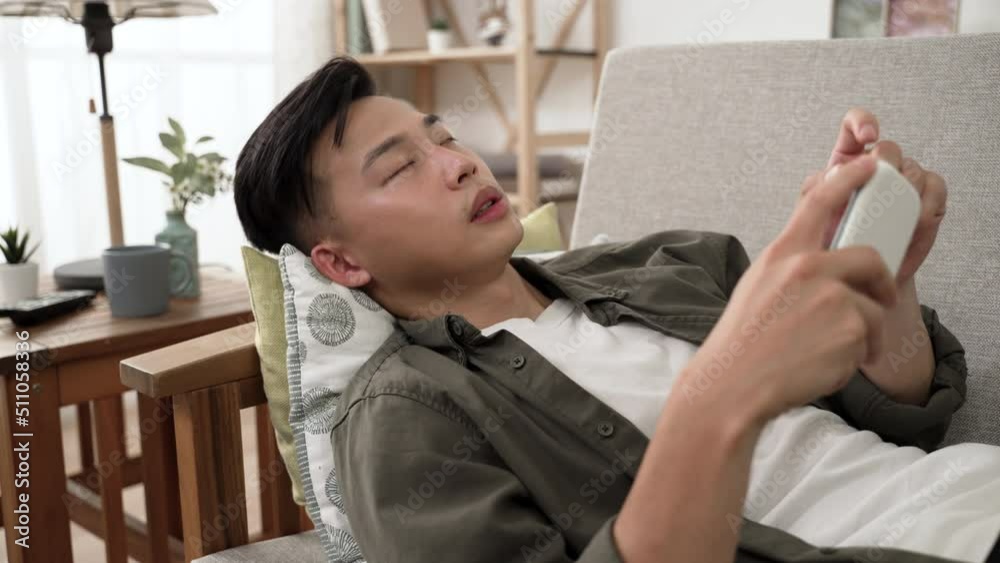 bored asian male staying at home alone during isolation is lying on ...