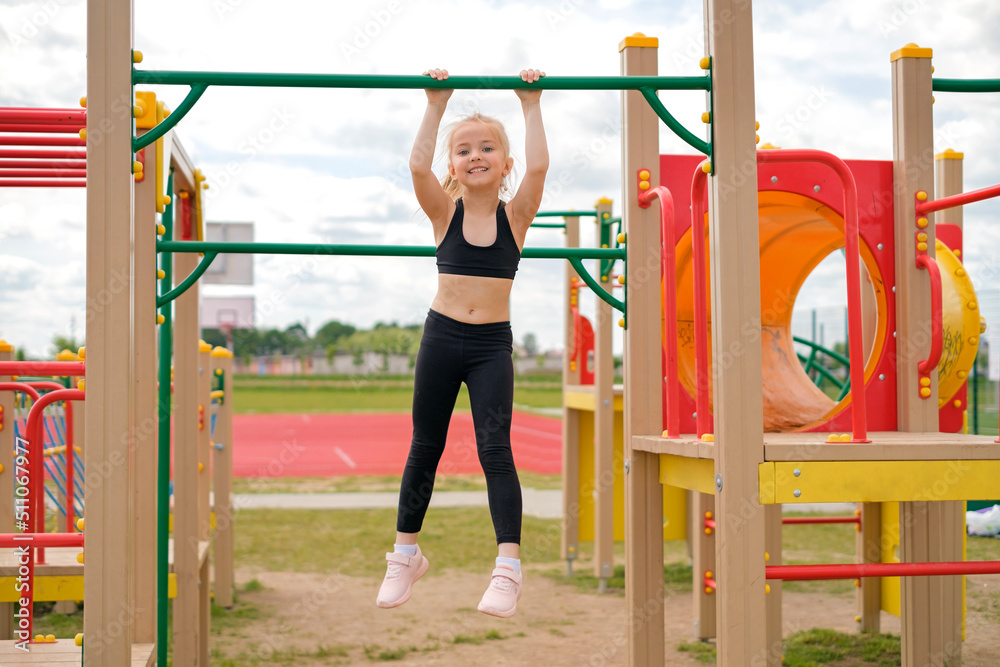 Young gymnast pulls up on a horizontal bar. A girl in a fitness and ...