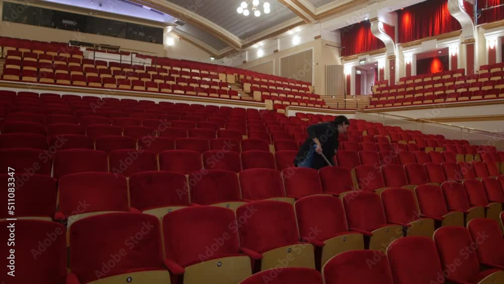 A woman cleaning at a theater opera house. The old theatre has red ...
